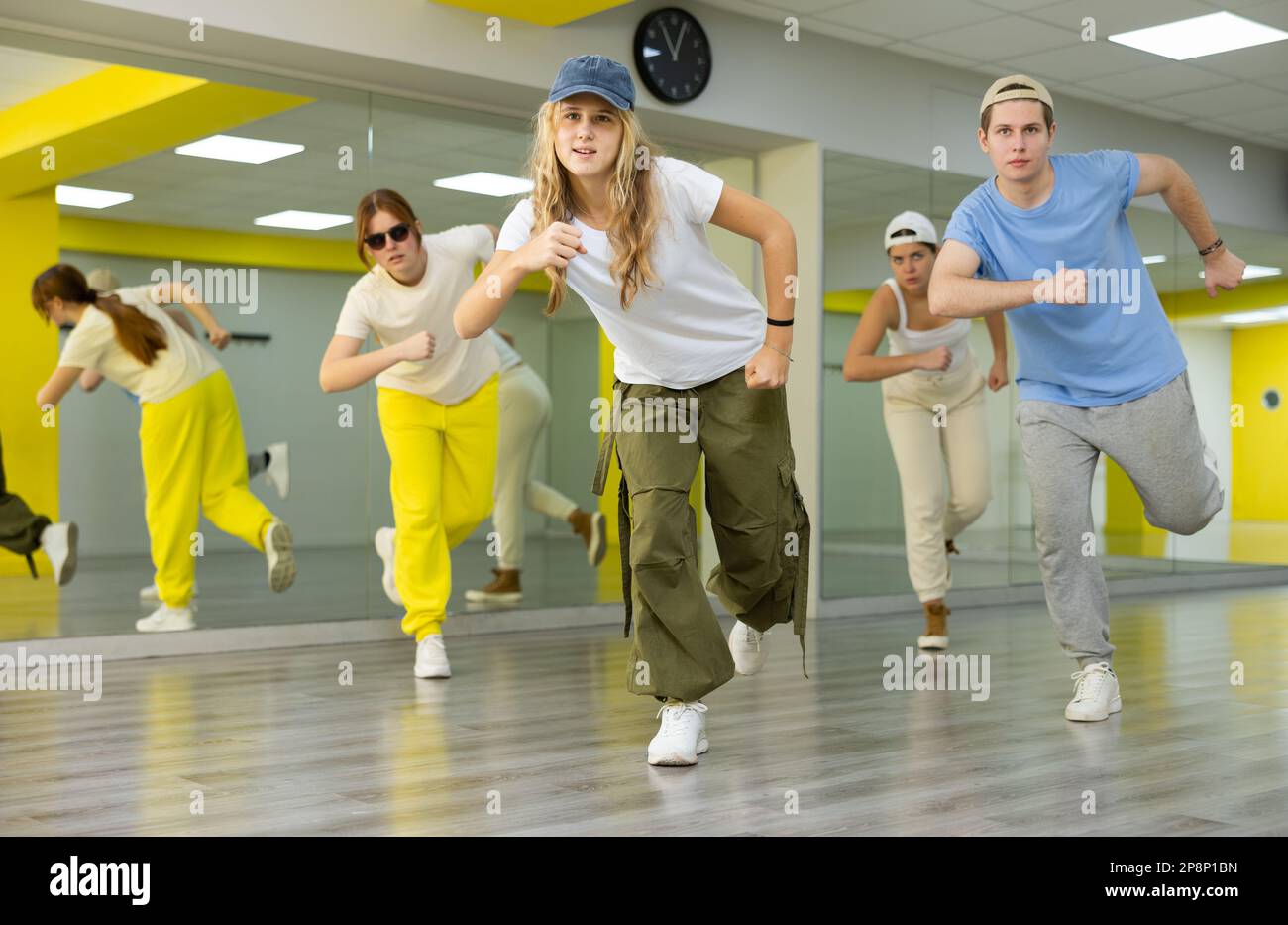Teenage girl in cap training breakdance Toprock moves in dance hall ...