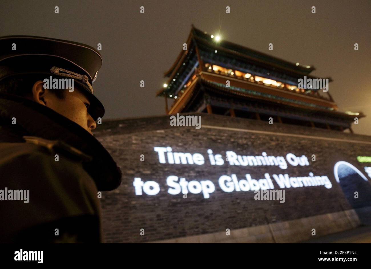 A security guard looks on as a slogan is projected onto Yongdingmen ...