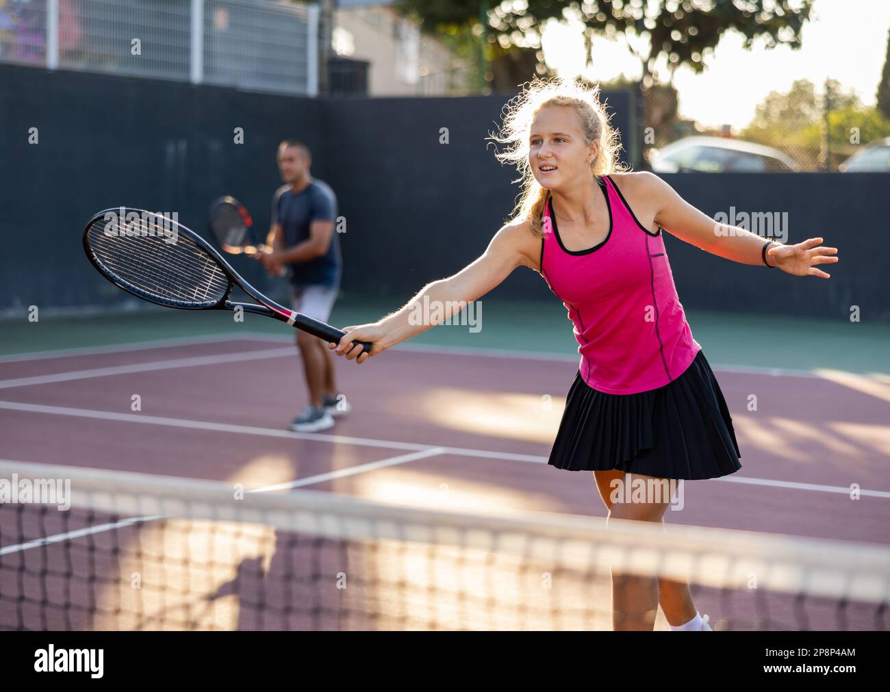 Sports active woman and her male partner playing tennis on court ...