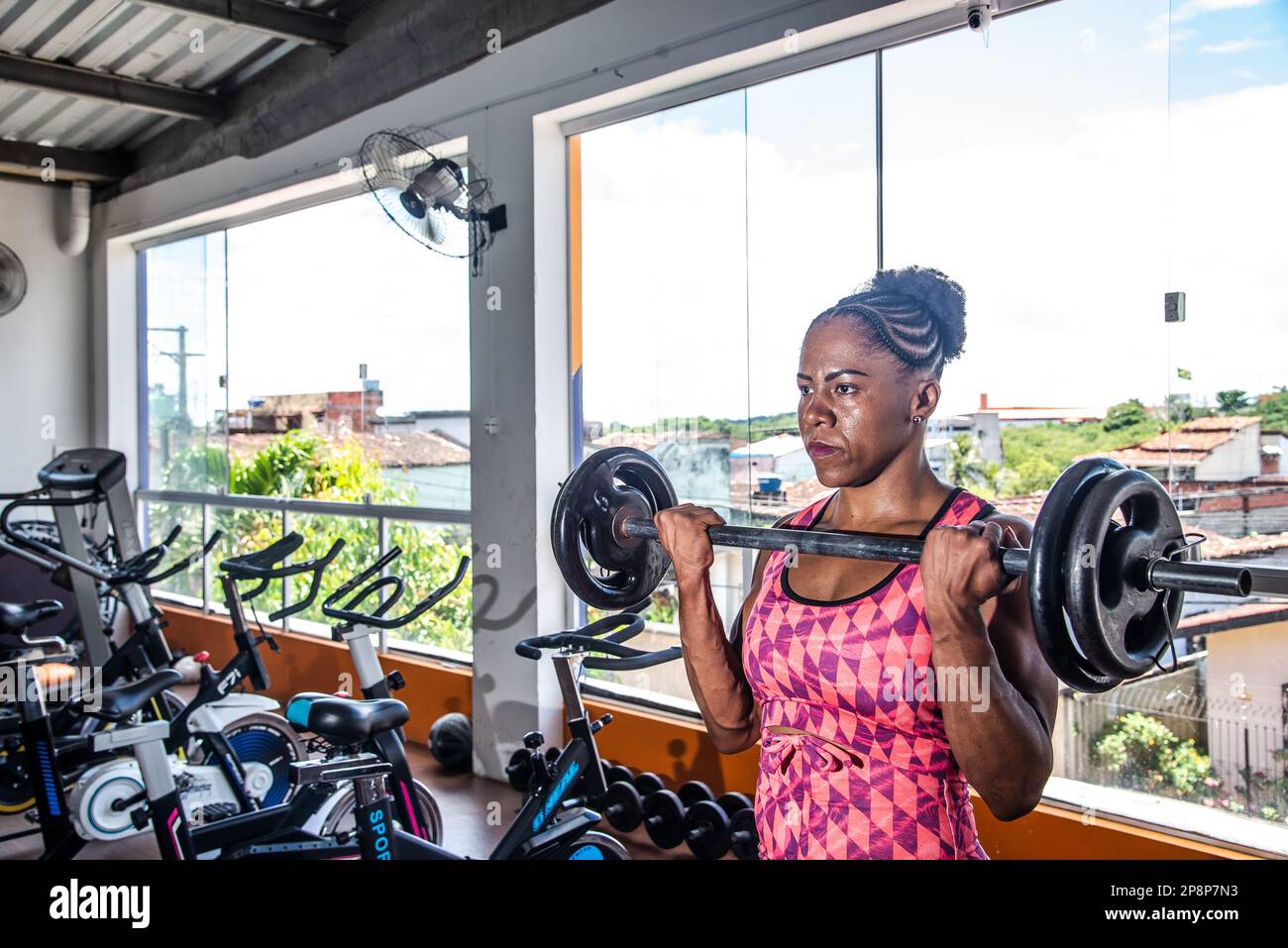 Determined woman lifting weights at the gym. Strengthening the arms ...