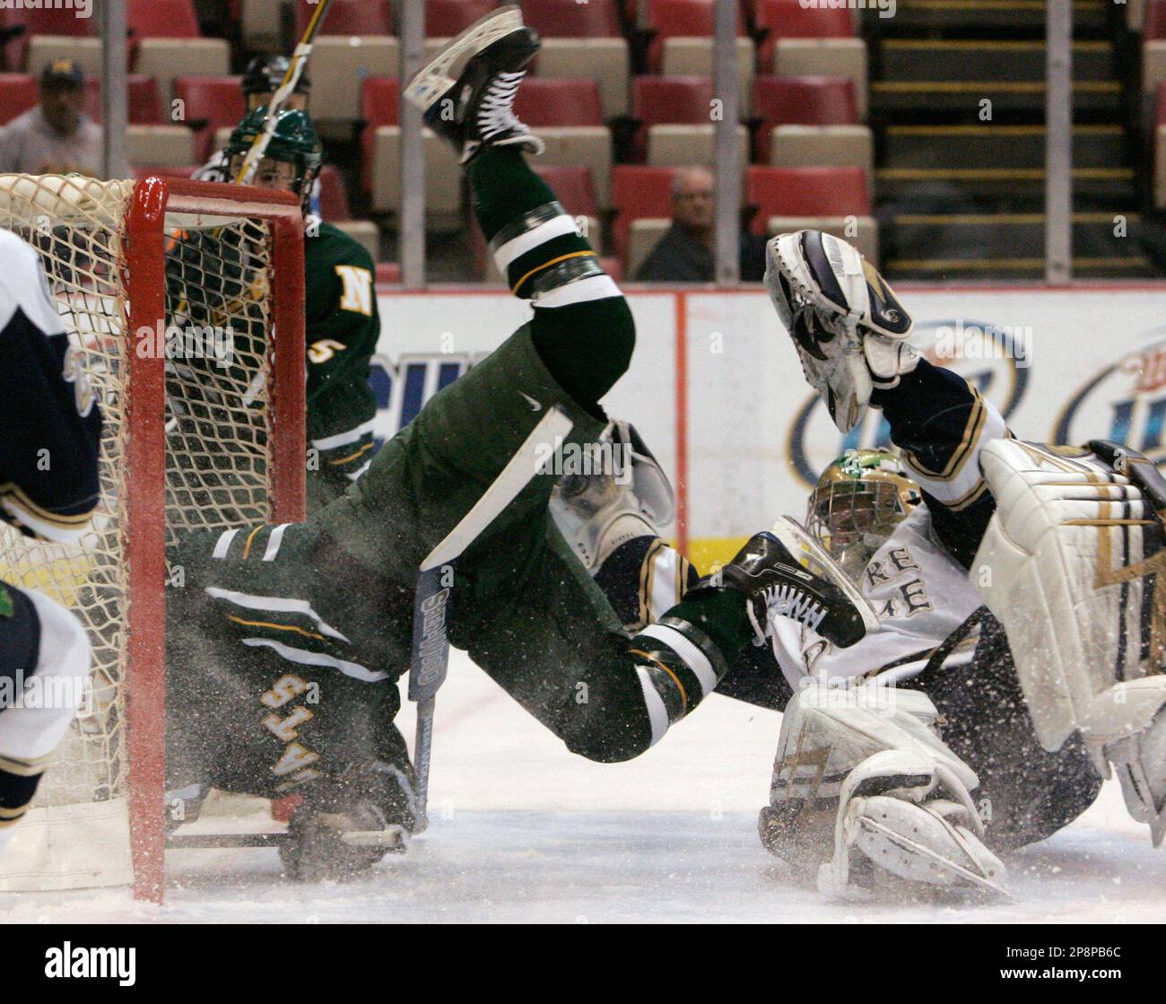 Northern Michigan center Mark Oliver flies into the net over Notre Dame ...