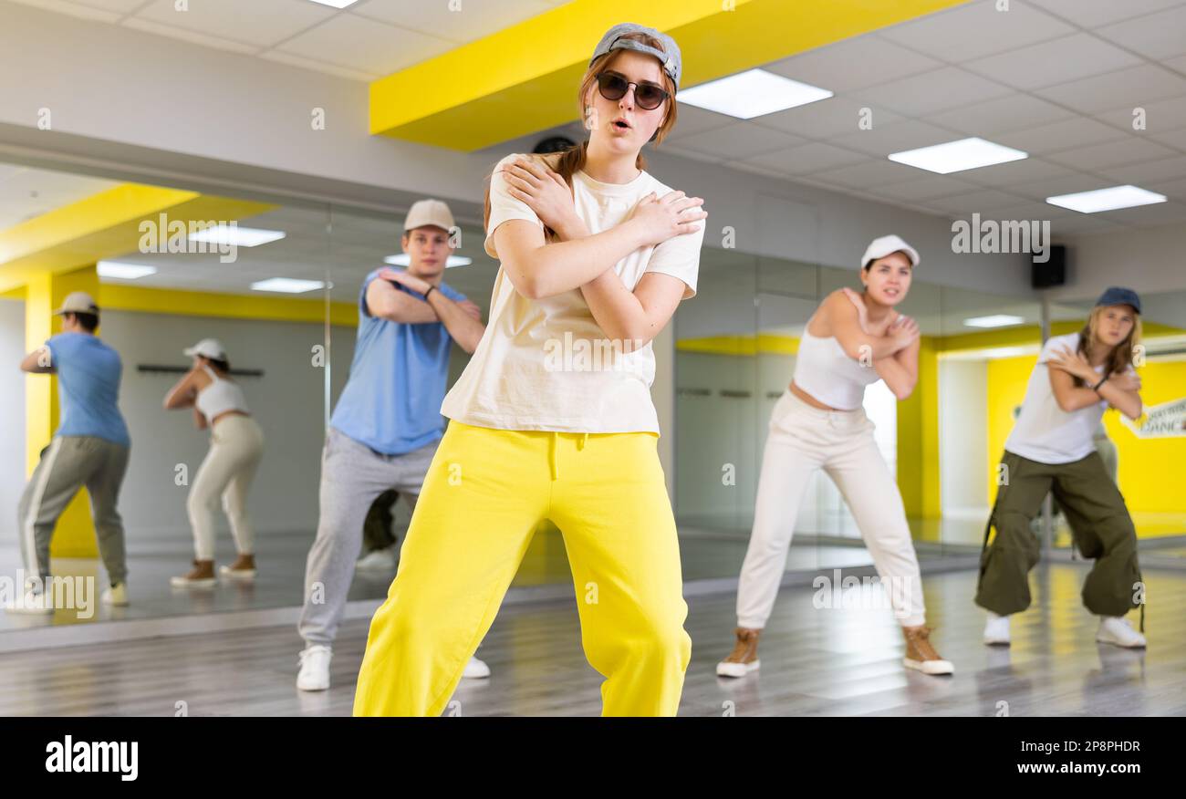 Confident sporty teenage dancers performing energetic dancing movements ...