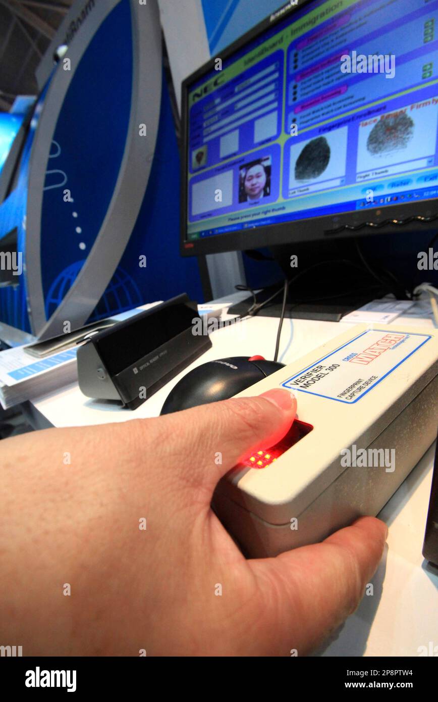 A man scans his thumbprint at a booth which showcases biometric ...