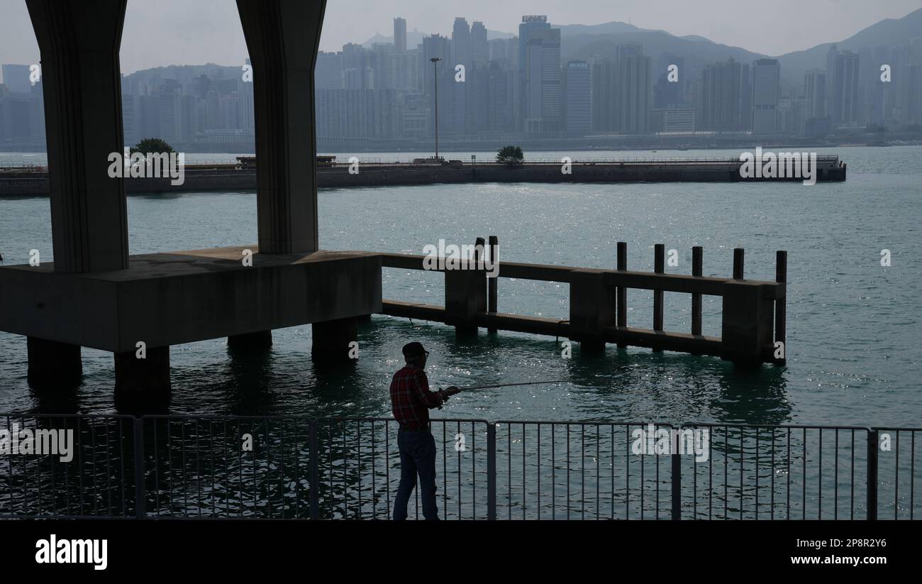 A man fishing at the waterfront of Victoria Harbour in Hung Hom ...