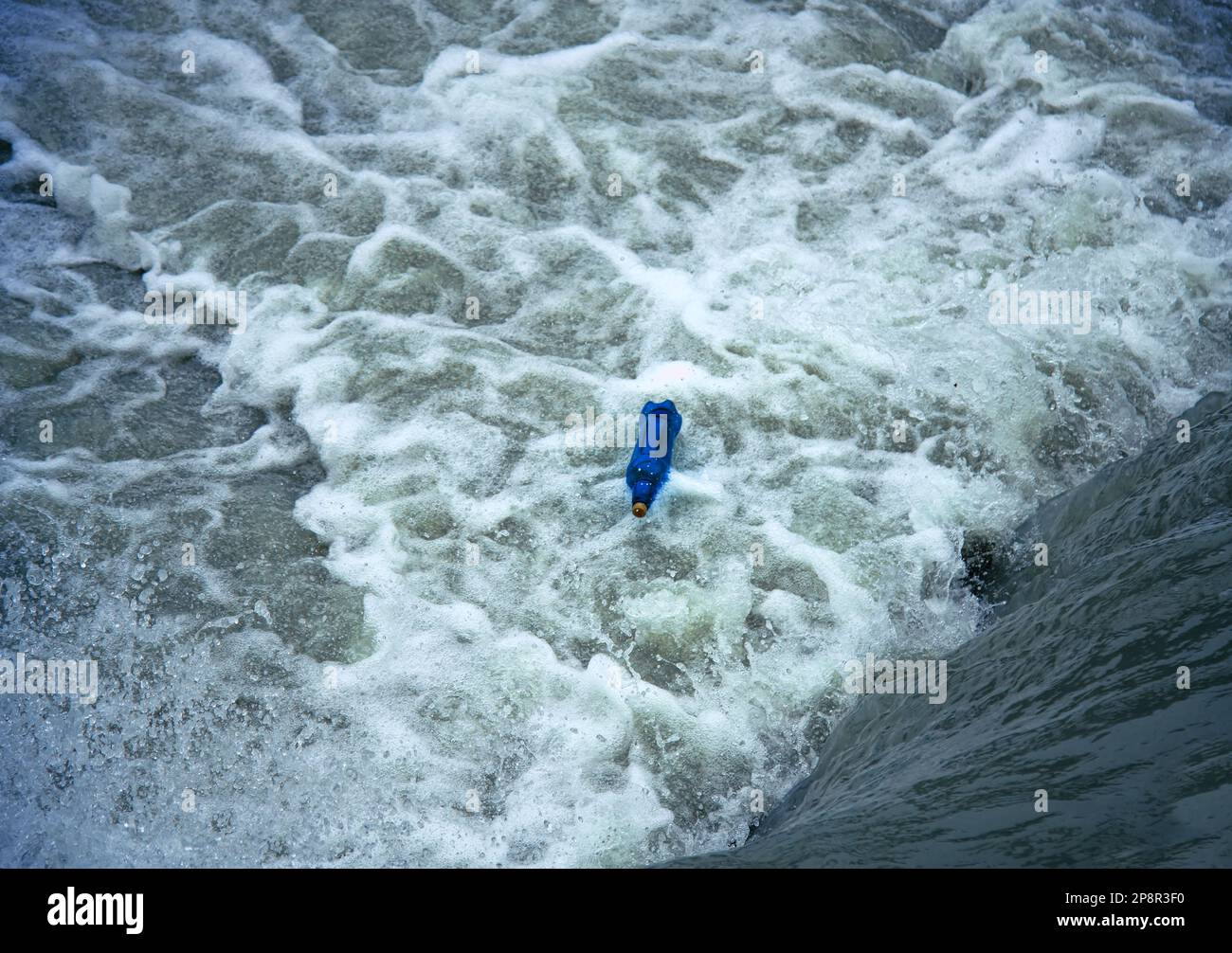 A waterfall and an empty plastic bottle tumbling in rough water ...