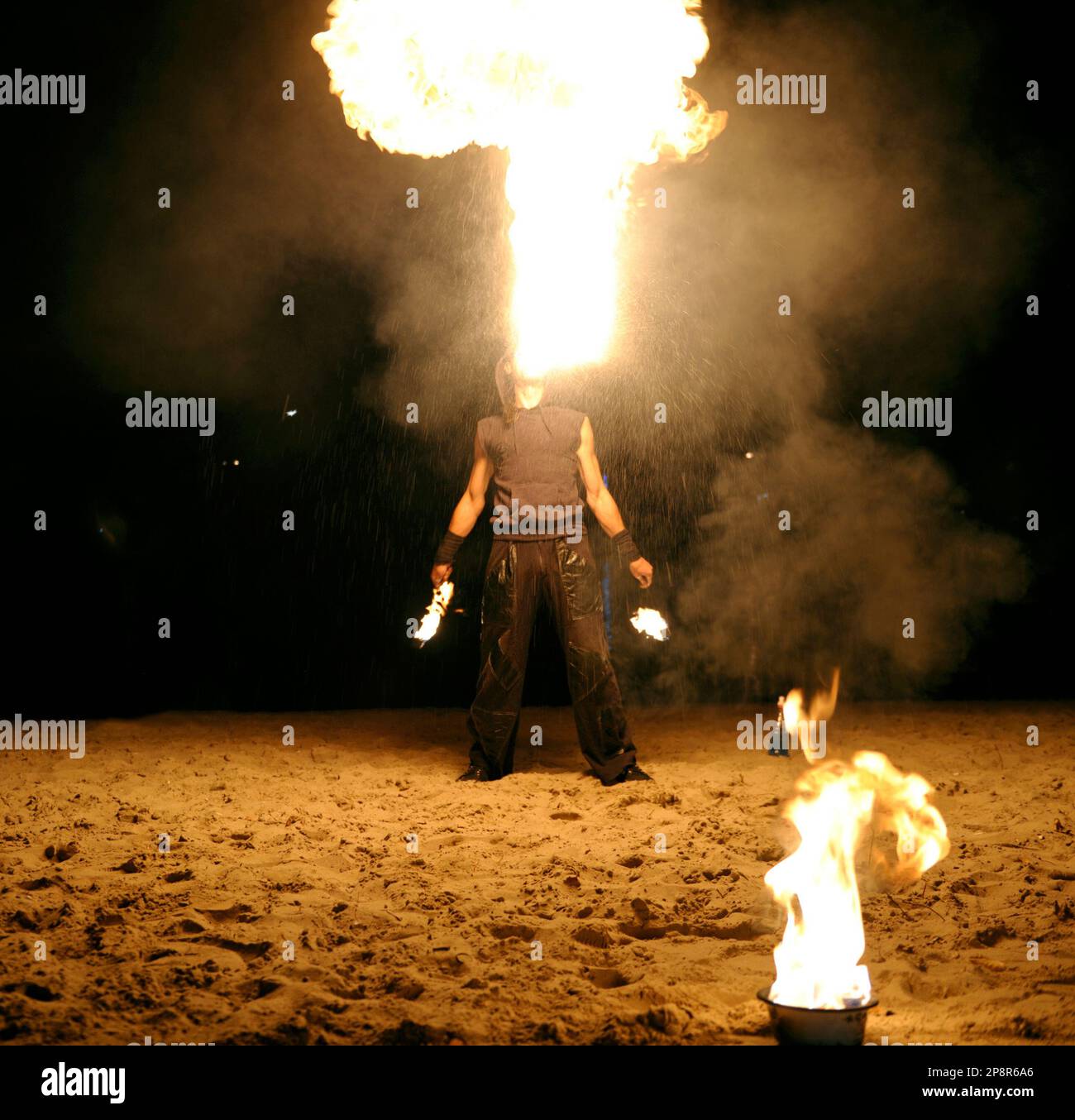 Man fire juggler performing at night on a sandy beach Stock Photo - Alamy