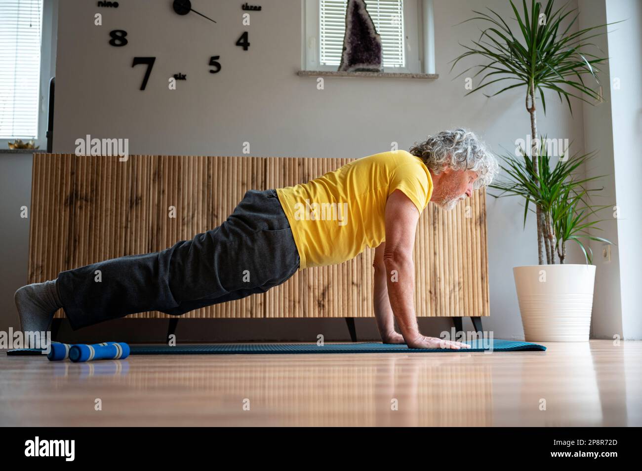 Side view of an active senior man in bright yellow shirt exercising at ...