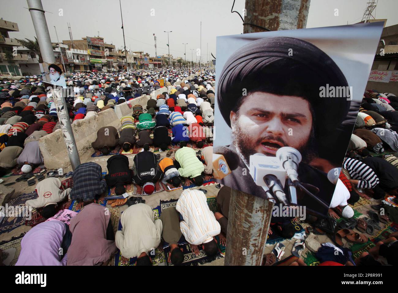 Iraqis pray under the portrait of radical Shiite cleric Muqtada al-Sadr ...