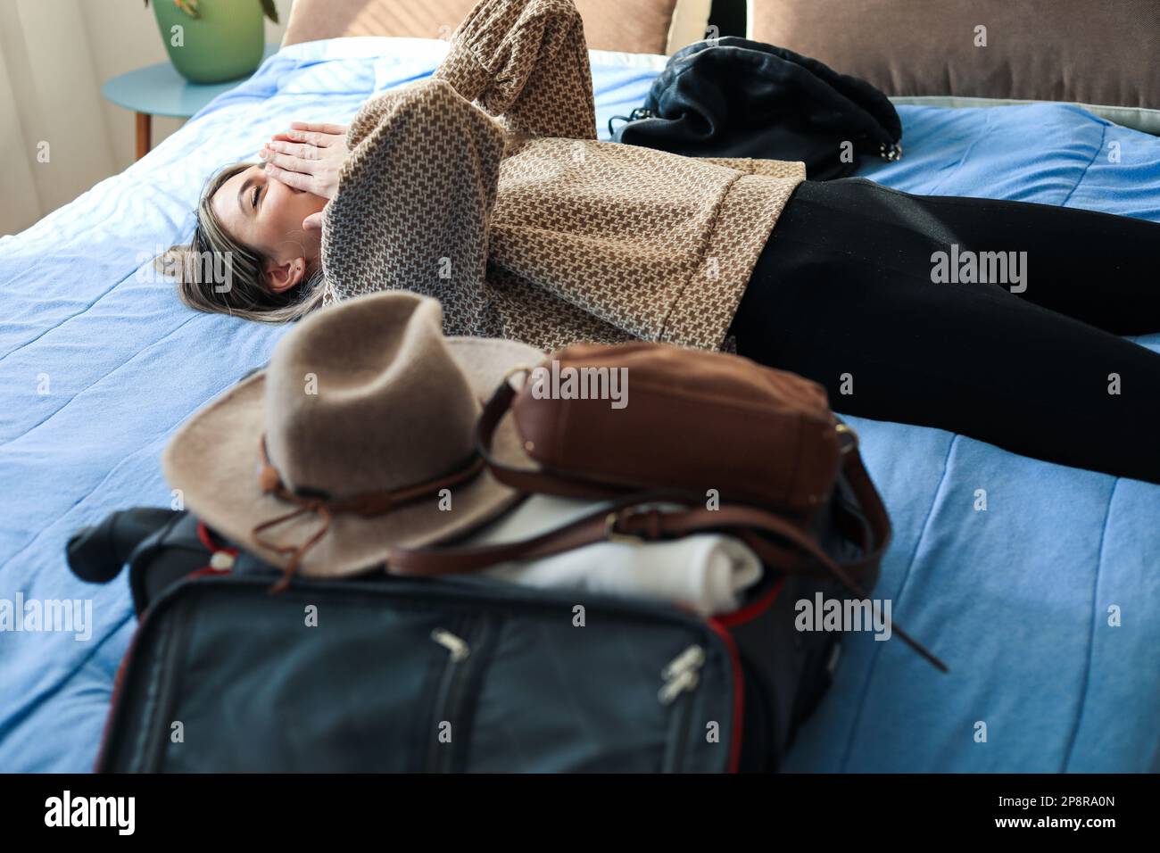 A young female preparing travel luggage and folding clothes in the room ...