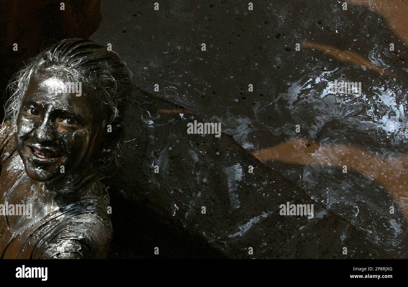 A girl, her face smeared with mud and color, looks on during ...