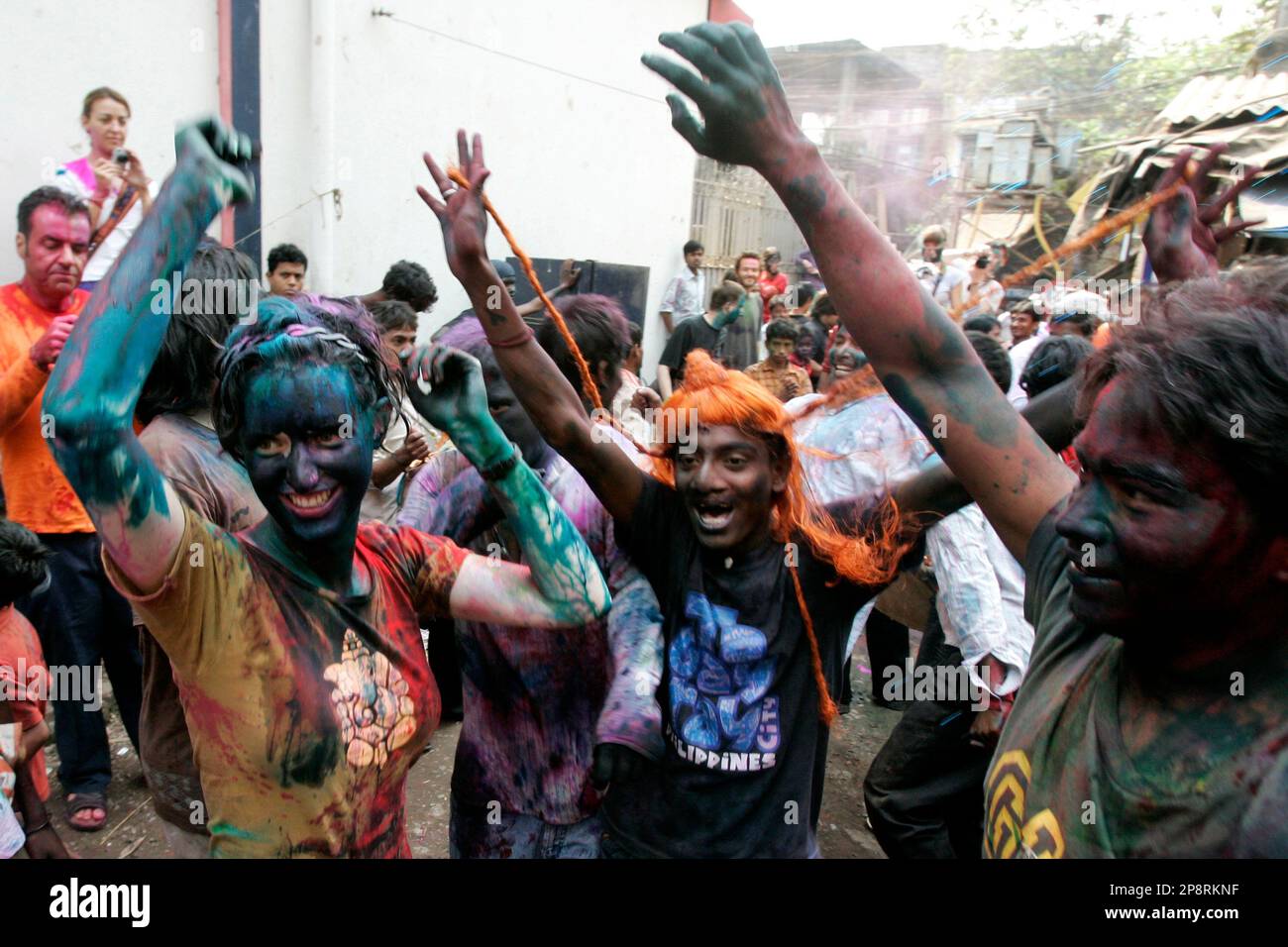 A foreign tourist, left, and Indians, their faces smeared with color ...