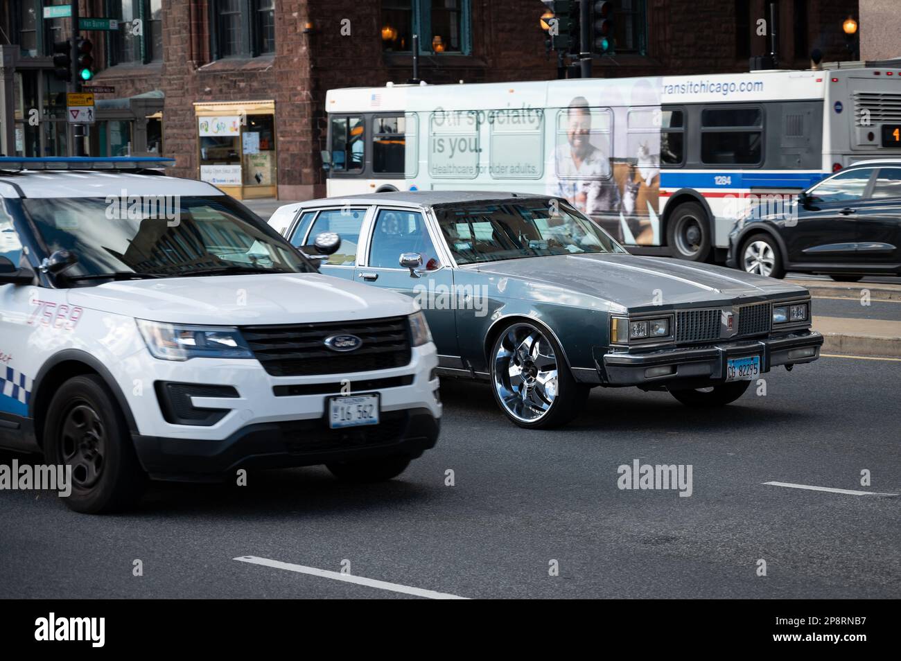 A modern police car with a vintage car parked on a city street Stock ...