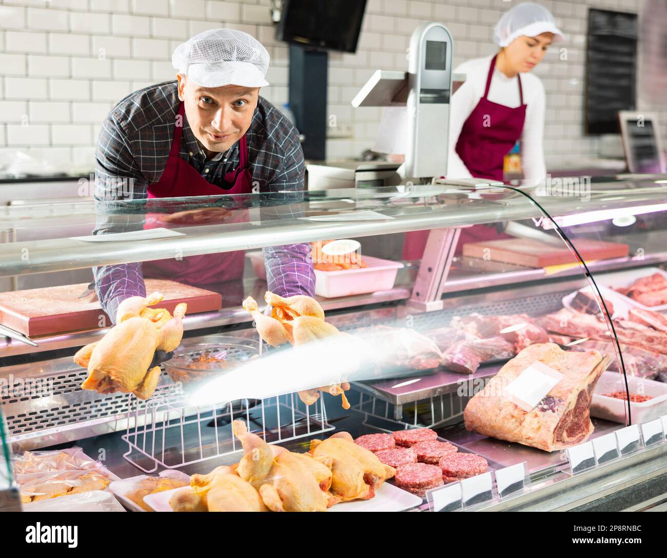 Adult butcher showing fresh gutted chickens in butchery Stock Photo - Alamy