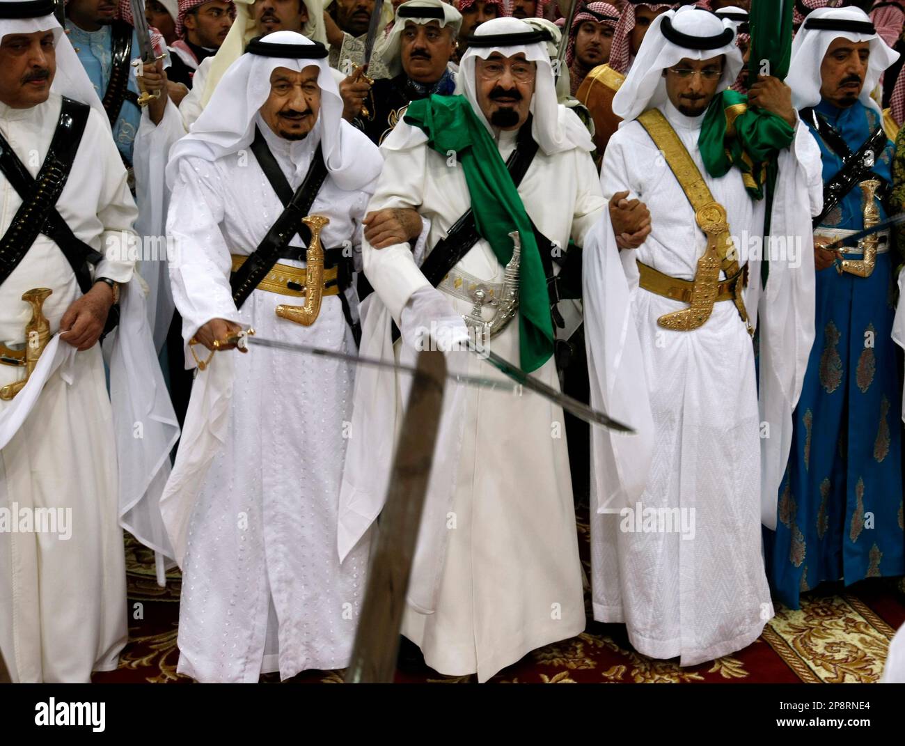 King Abdullah of Saudi Arabia, center, raises his sword as he takes ...