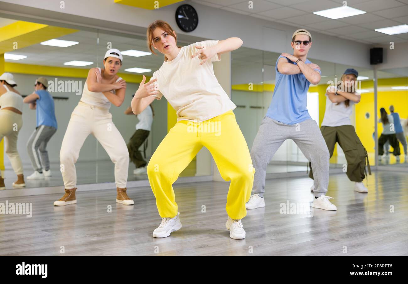 Cool talented teens in casual wear exercising modern dance moves in ...