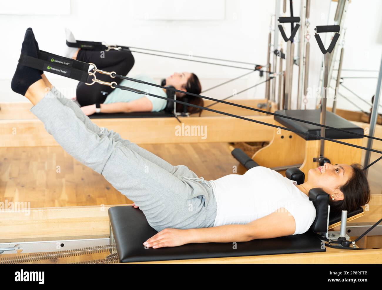 Sportswoman stretching body on pilates chair while doing forward bends ...