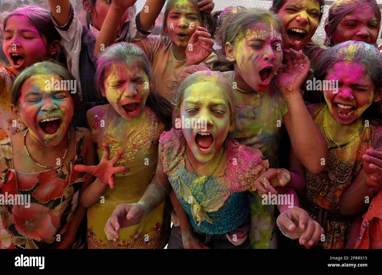 School children with their faces smeared with colored powder react to ...