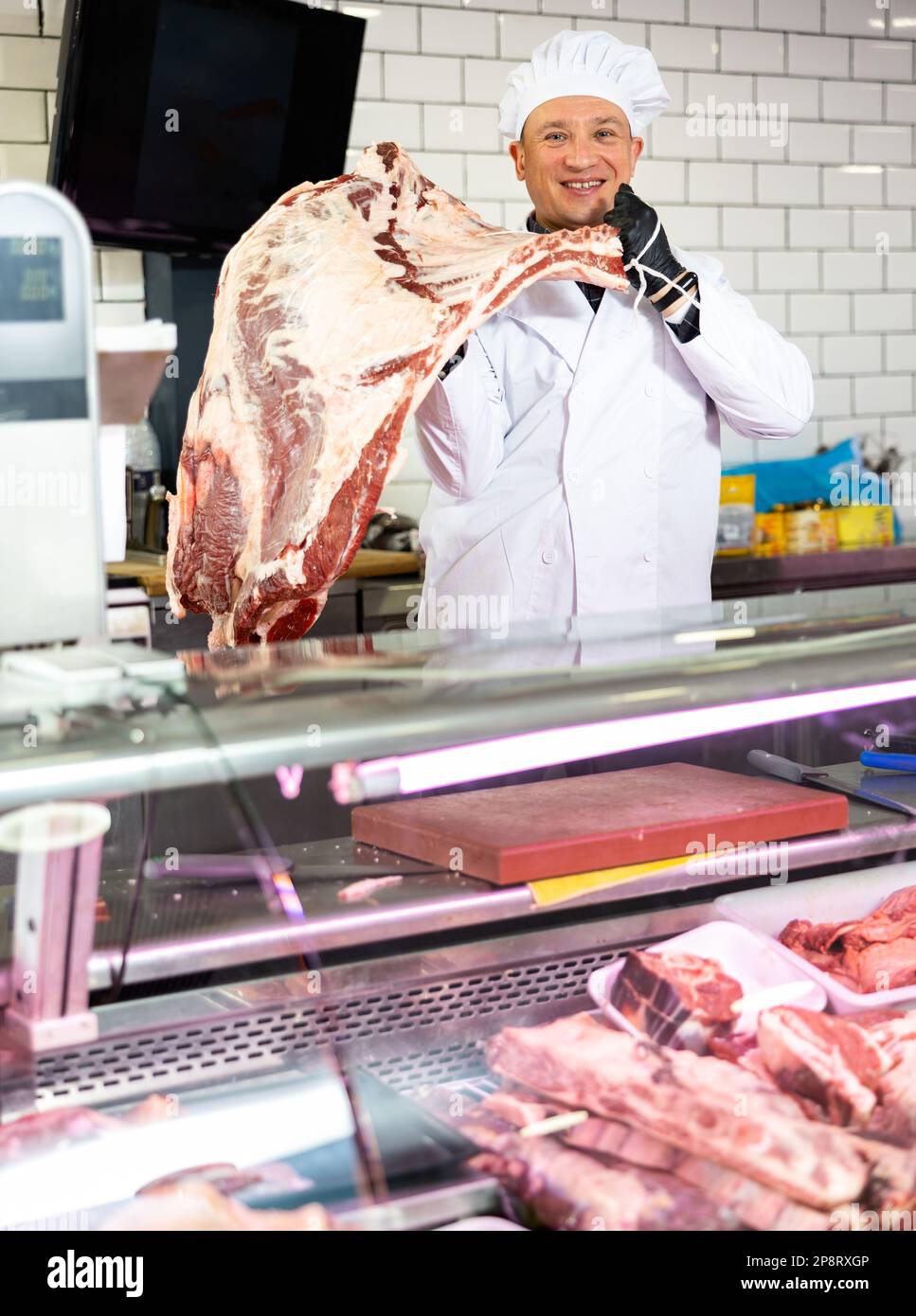 Adult man puts beef ribs in showcase Stock Photo - Alamy