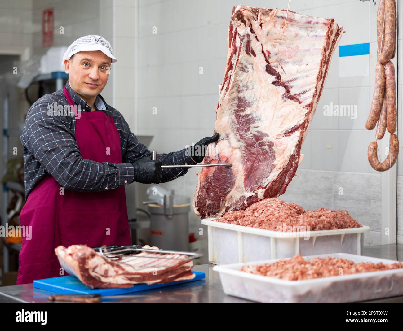 Confident male butcher holding big chunk of beef ribs is prepared in ...