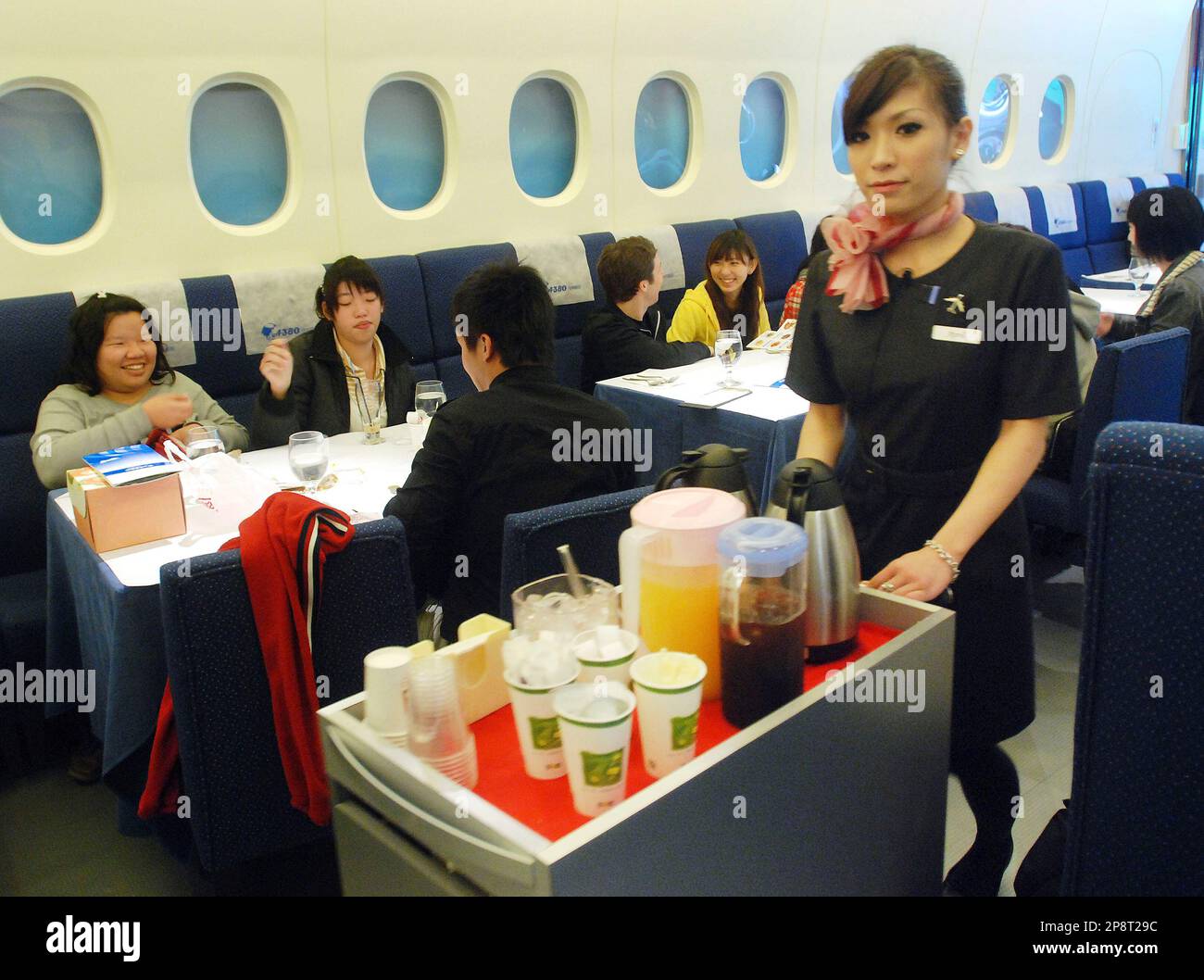 A waitress in a flight attendant's uniform serves a meal to customers ...