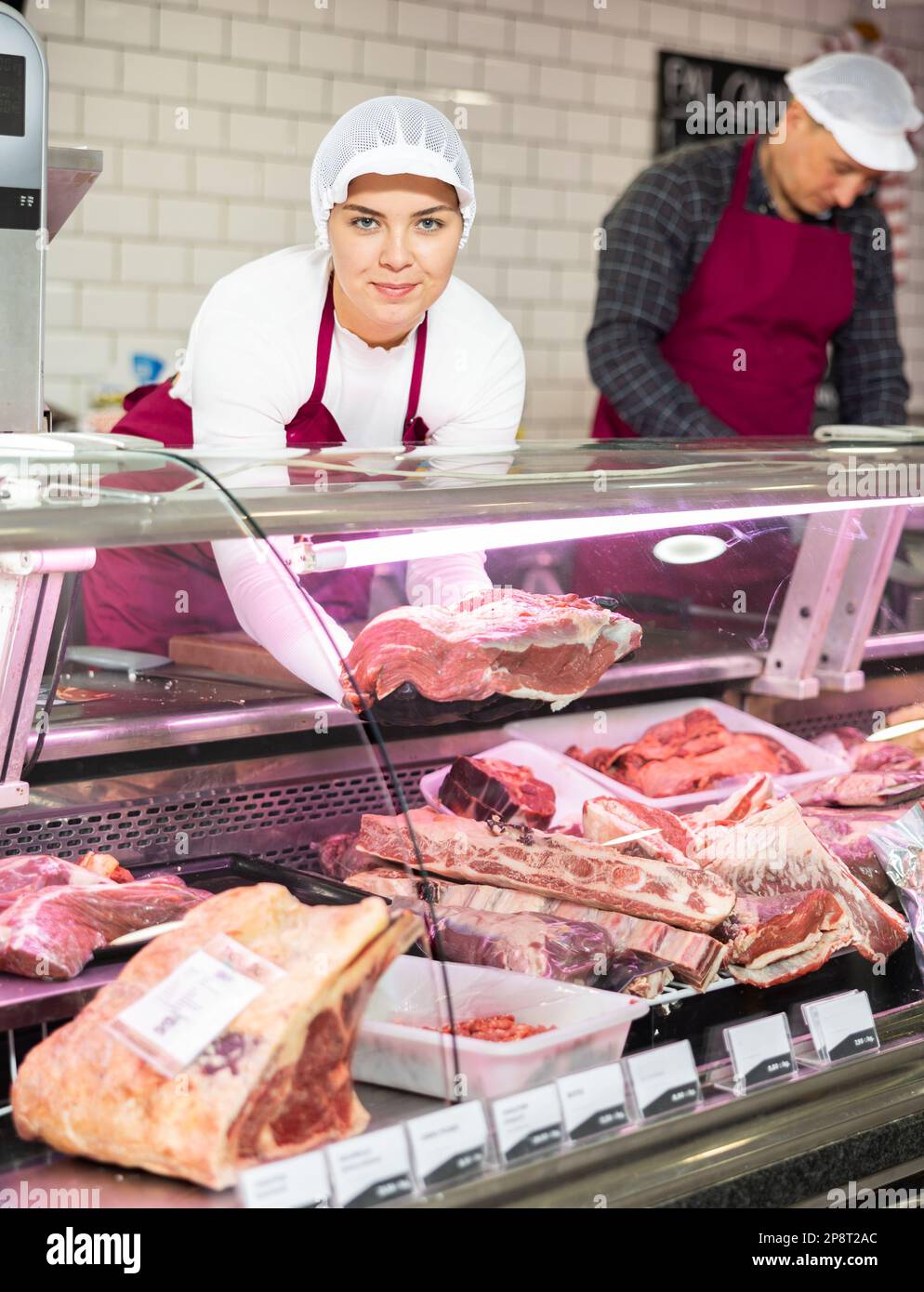 Female butcher choosing slice of raw veal sirloin for customer Stock ...