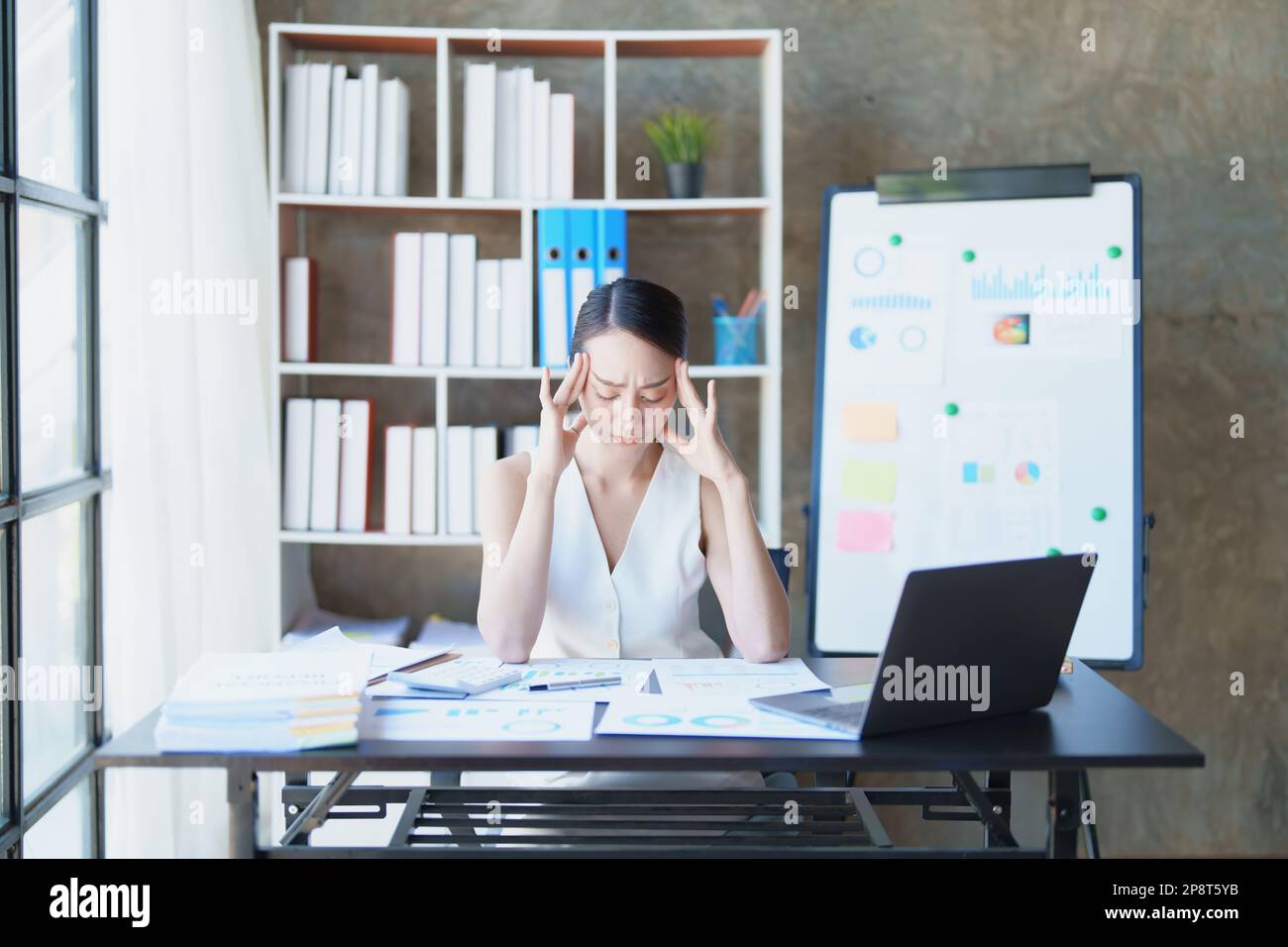 Portrait of a young Asian woman showing acute headache from sitting for ...