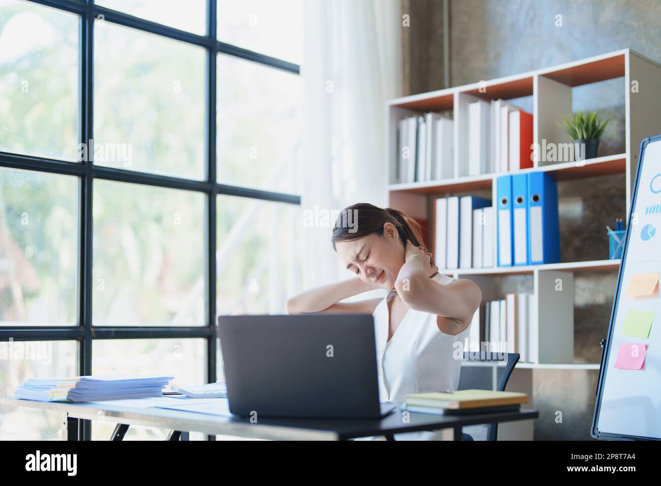 Portrait of a young Asian woman suffering from acute headache and ...