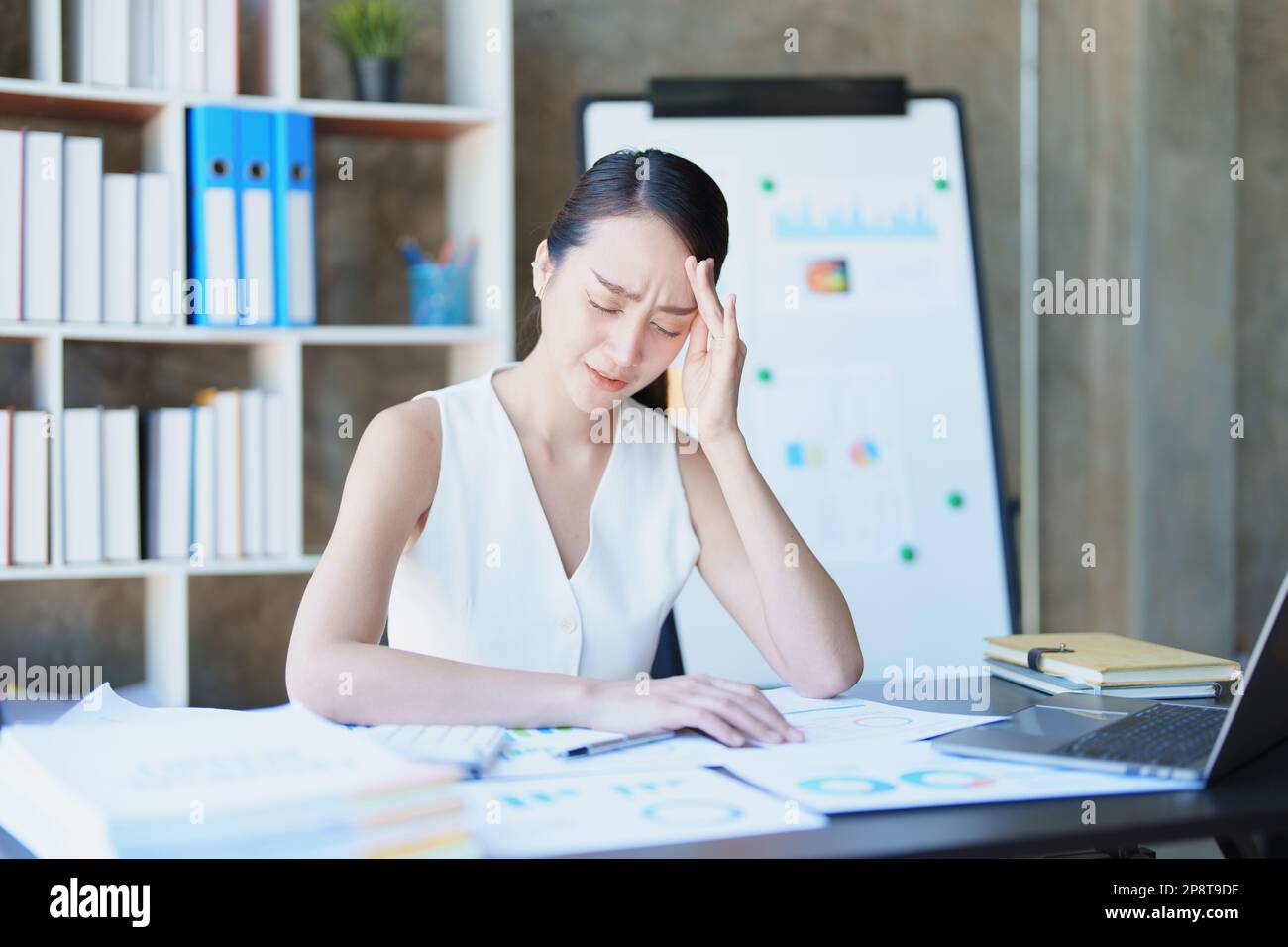 Portrait of a young Asian woman showing acute headache from sitting for ...