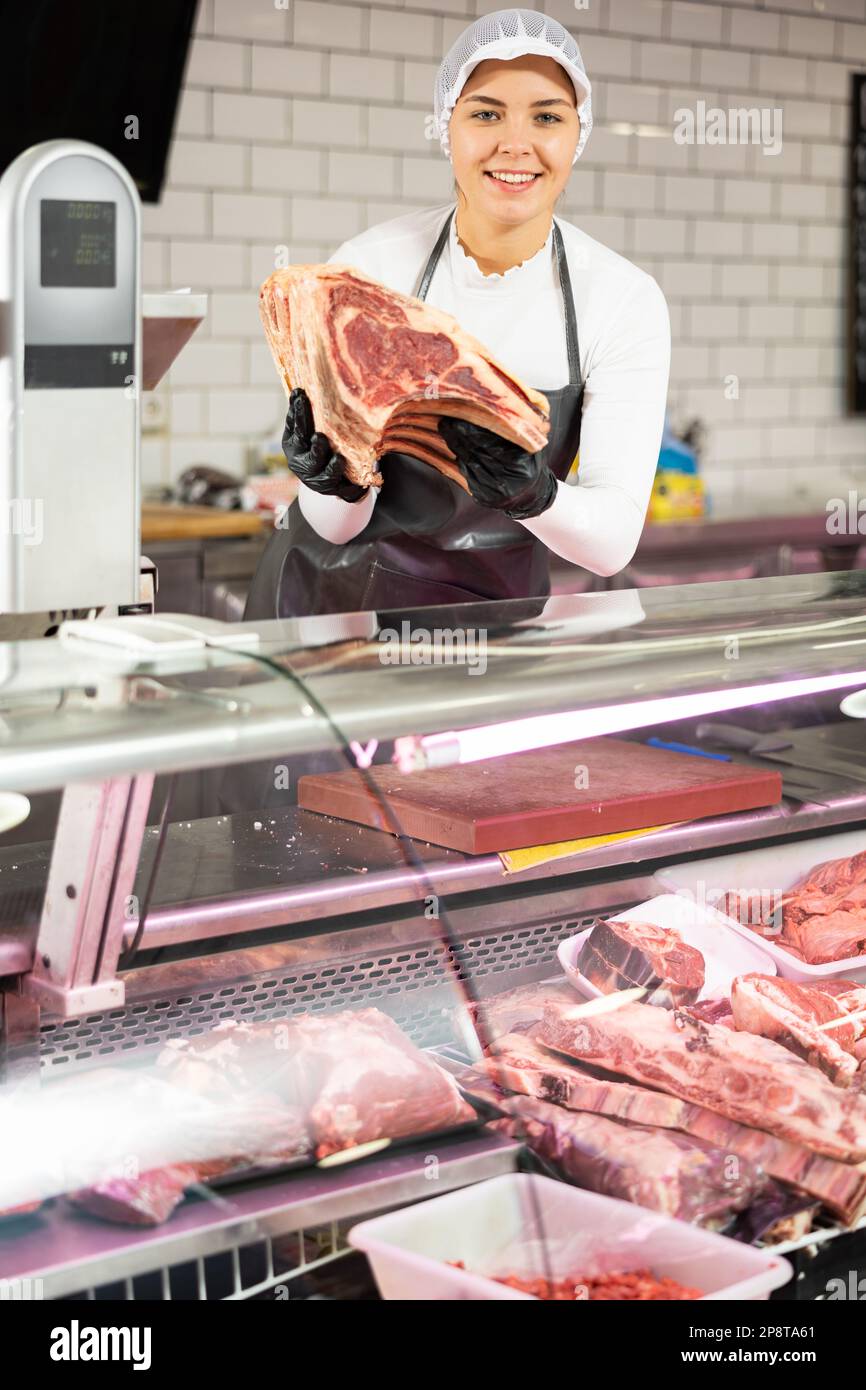 Female butcher demonstrating fresh raw veal chop on ribs Stock Photo ...
