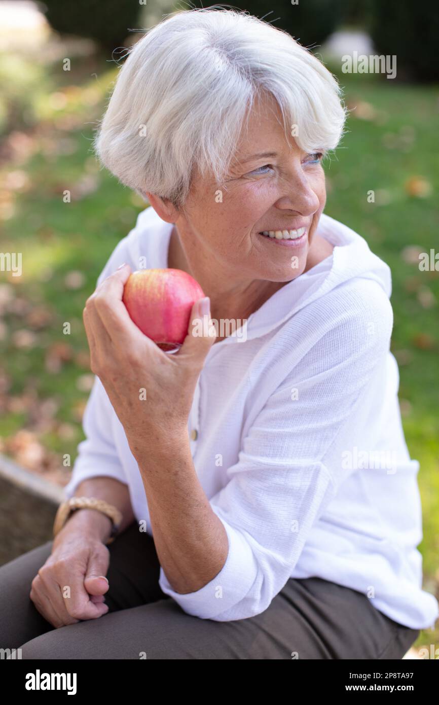 healthy senior woman eating an apple outdoors Stock Photo - Alamy
