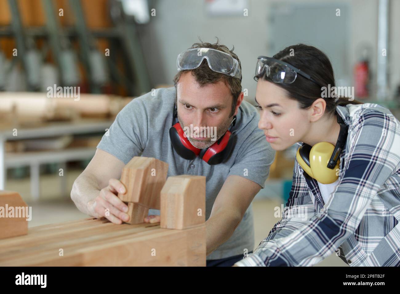 carpenter training female apprentice to use mechanized saw Stock Photo ...