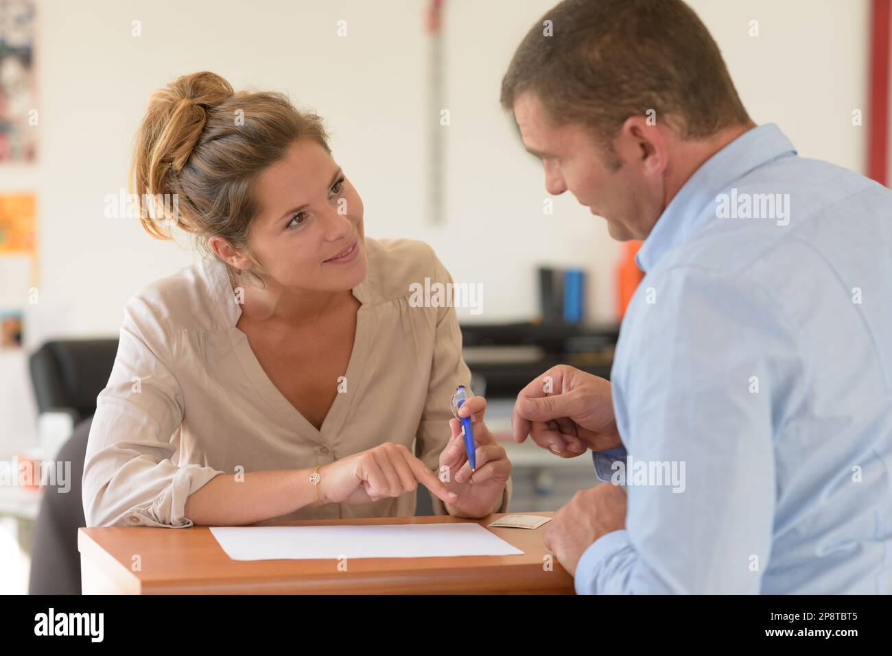 secretary helping male customer to complete paperwork Stock Photo - Alamy