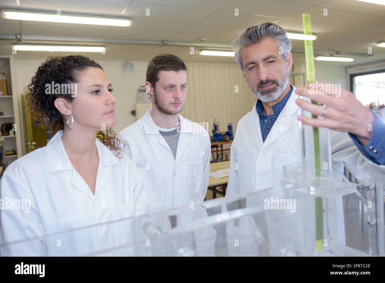 teacher with teenage students experimenting at desk in lab Stock Photo ...