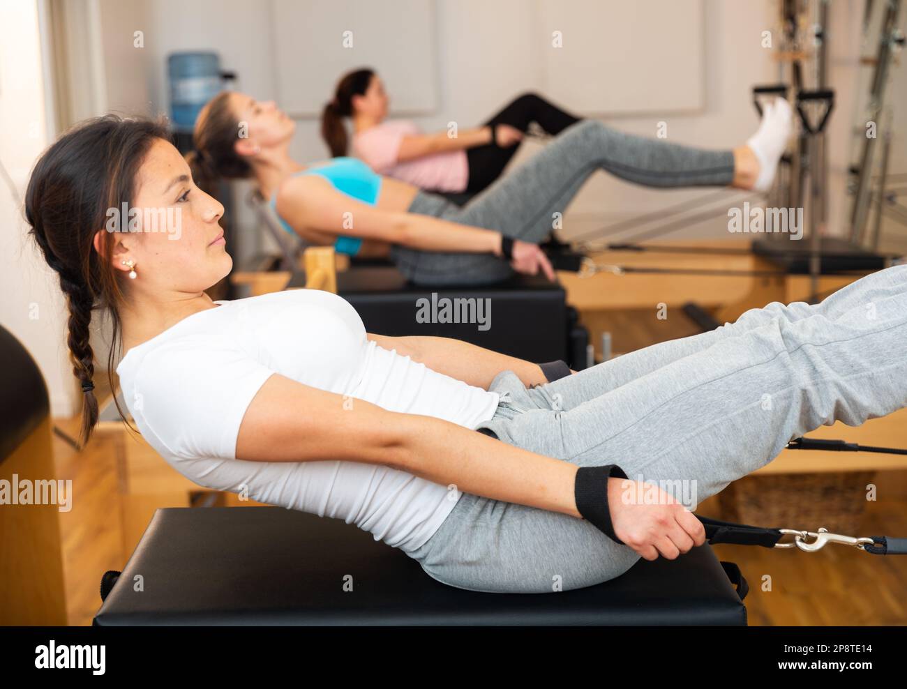 Sportswoman stretching body on pilates chair while doing forward bends ...