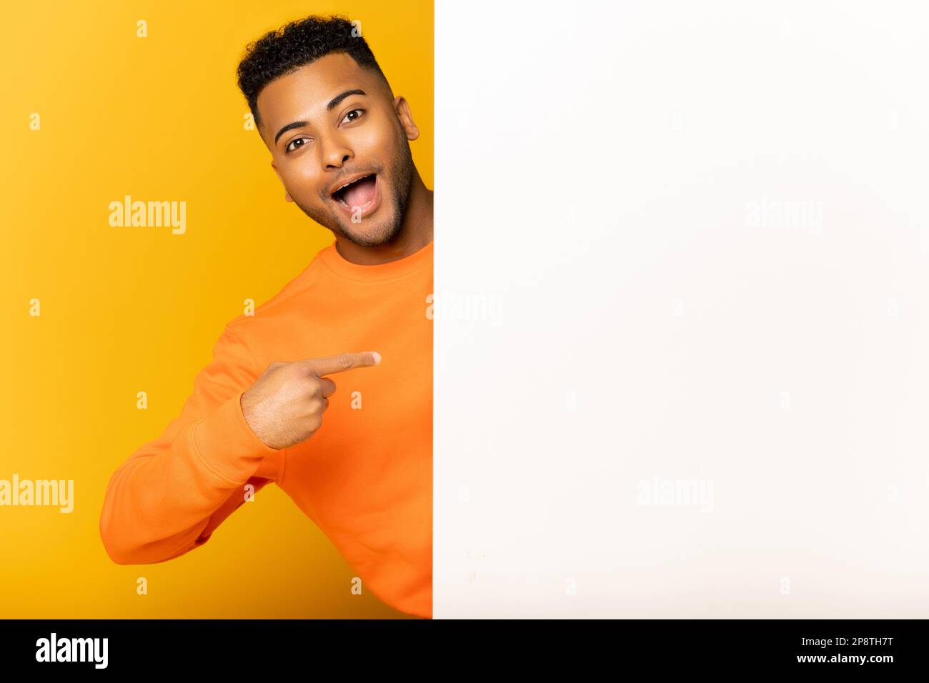 Surprised smiling handsome indian man peeking out from behind empty ...