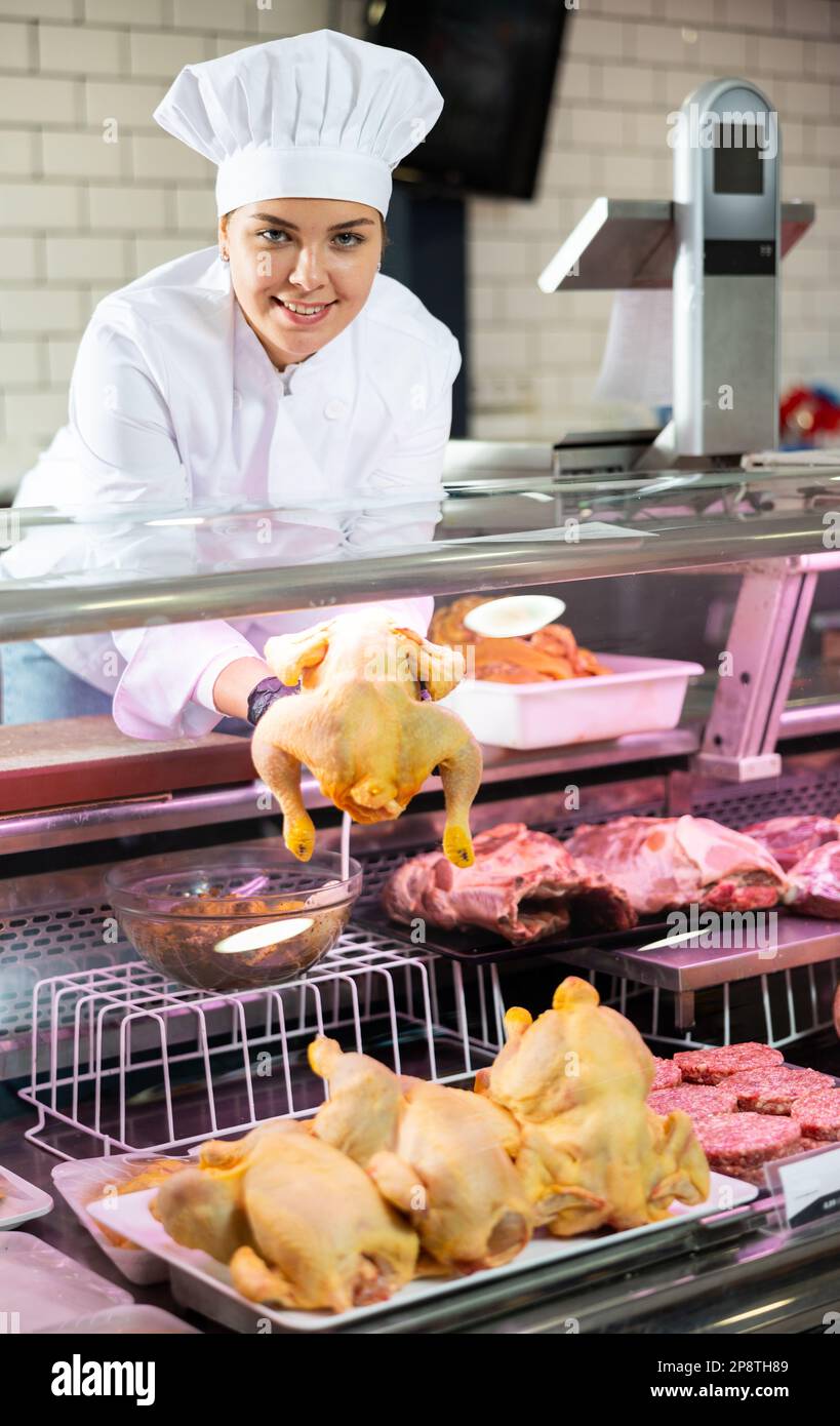 Young female butcher showing fresh whole chicken in butchery Stock ...