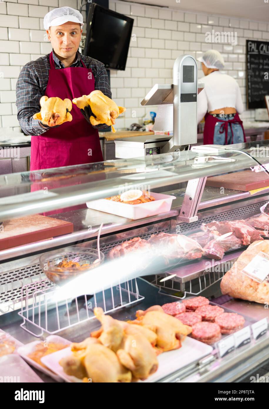 Male butcher showing fresh whole chicken in butchery Stock Photo - Alamy