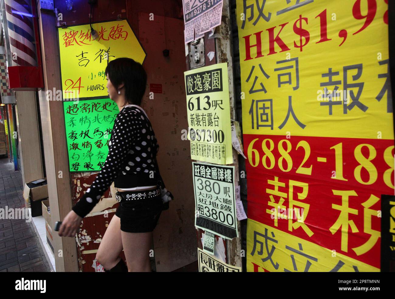 **APN ADVANCE FOR MARCH 8** A woman walks by hand-written signs advertising a prostitution ...