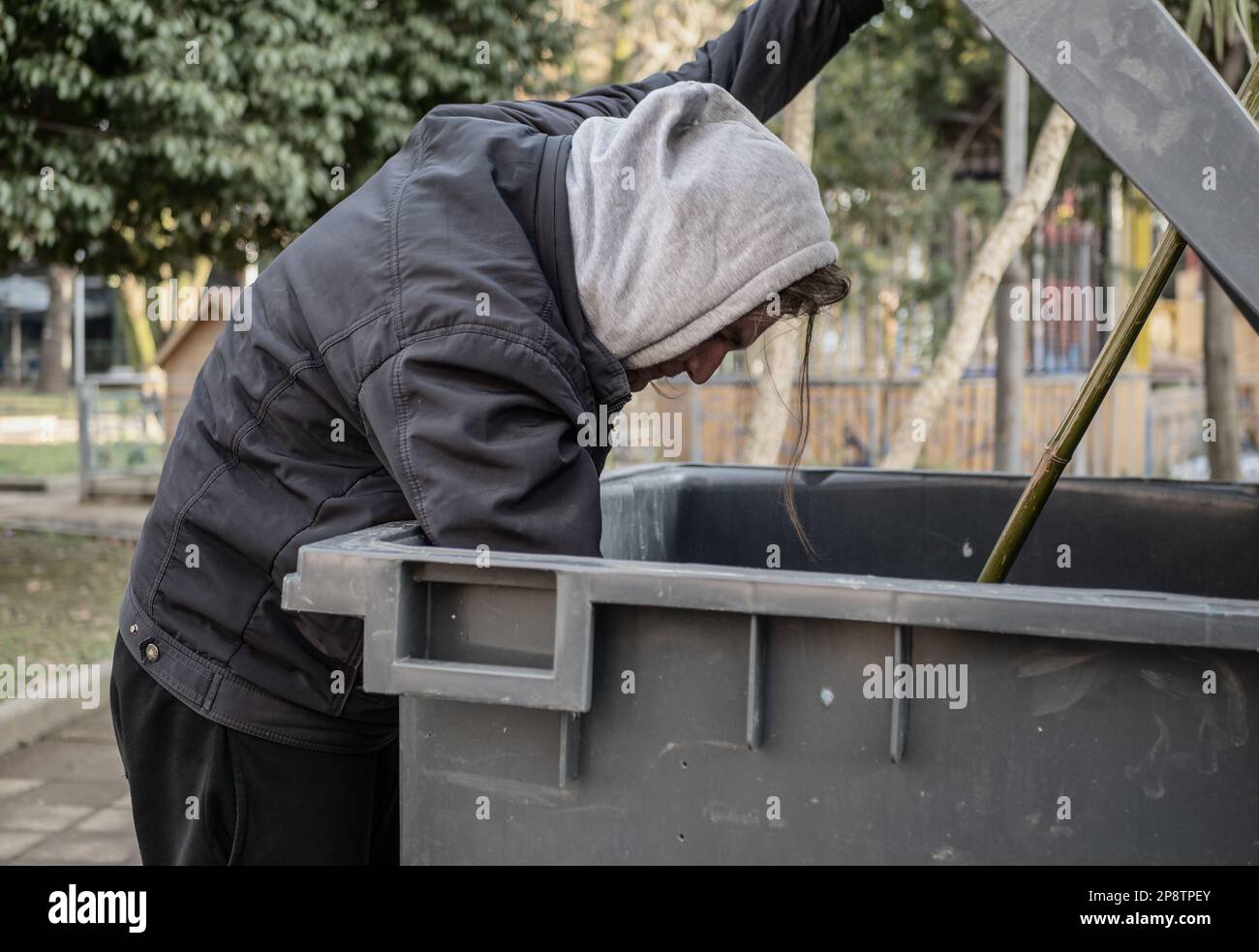 Hungry homeless man rummaging in trash can looking for food Stock Photo ...