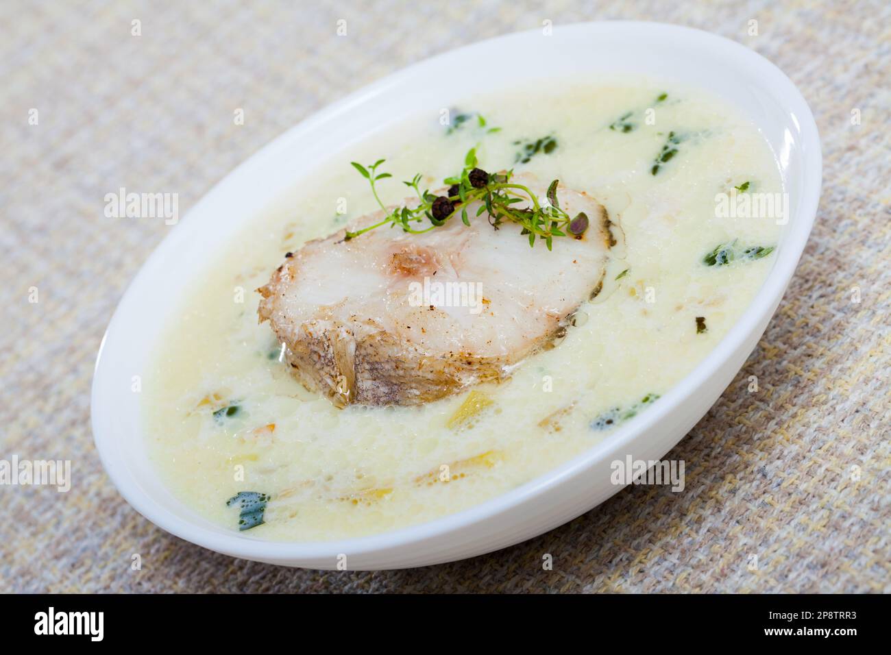 Boiled creamy soup with white fish pollock and greens at plate Stock ...