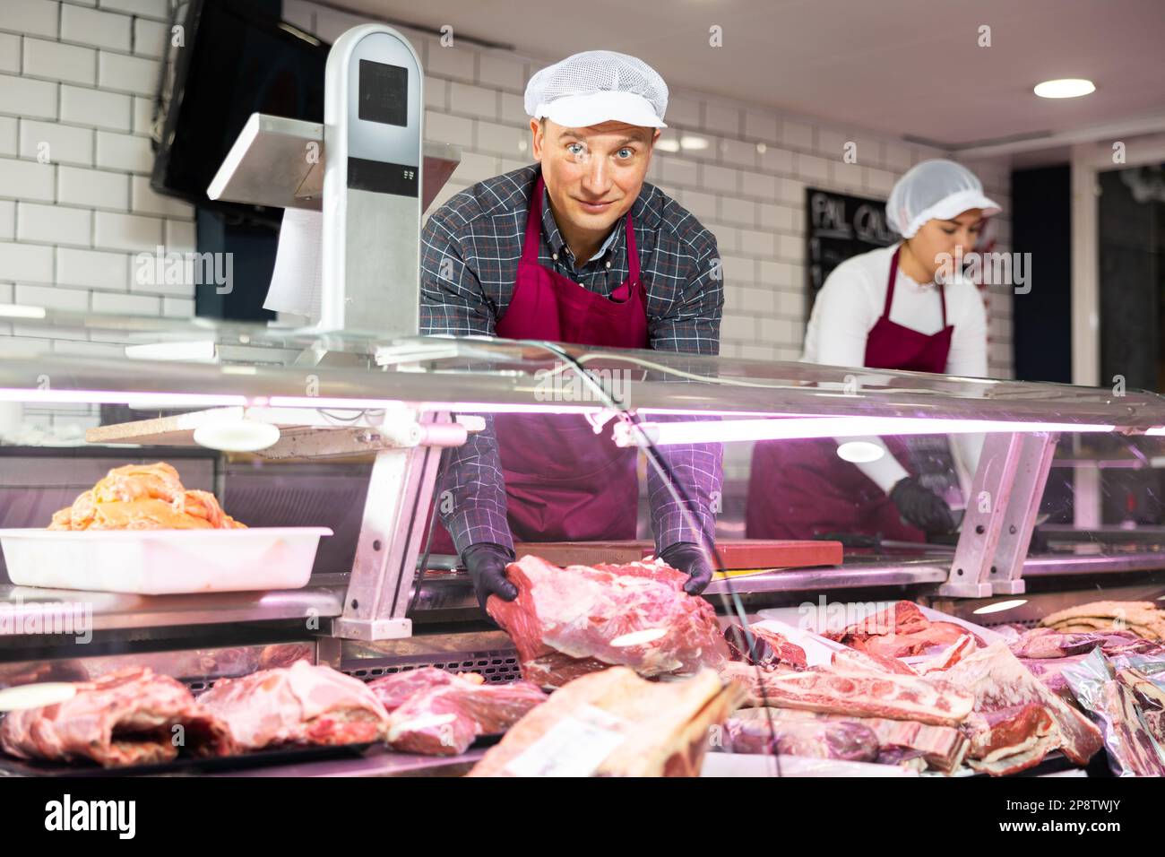 Adult man puts beef ribs in showcase Stock Photo - Alamy