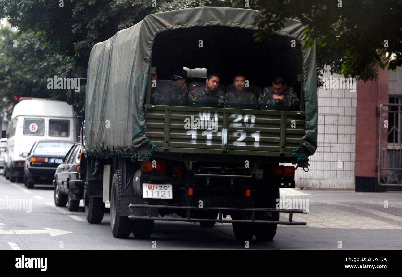 Chinese paramilitary police officers sit behind riot shields in a truck ...