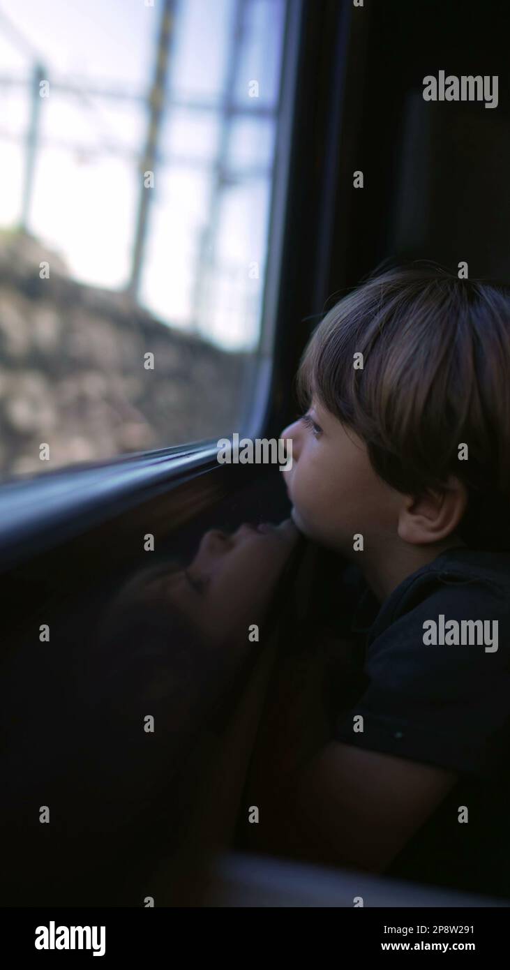 One small boy traveling by train. Child staring out window in motion ...