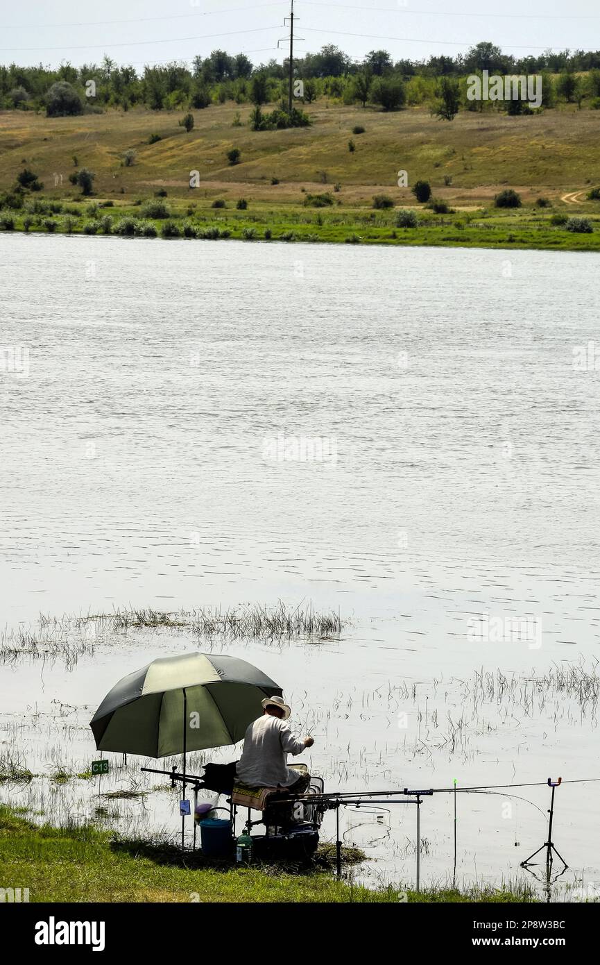Fishing Competition. Fisherman catches fish, sheltering from sun under ...