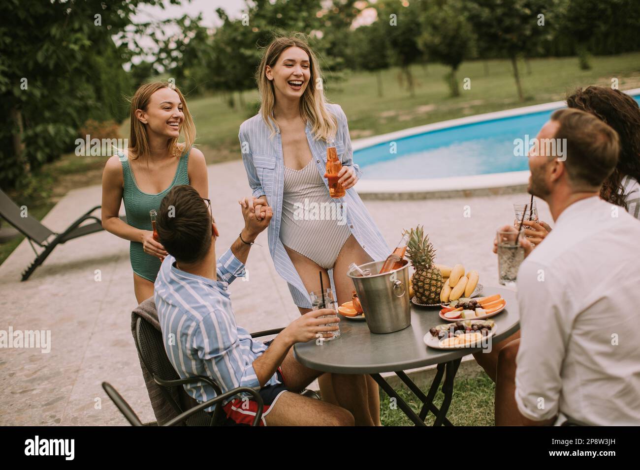 Group of happy young people cheering with cider by the pool in the ...