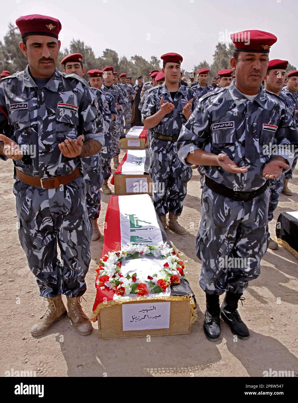 Iraqi security forces pray next to the coffins of Iraqi soldiers who ...