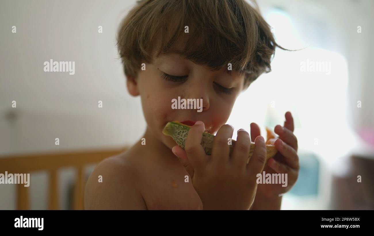 Child biting melon fruit dessert. One young boy eating healthy tasty ...