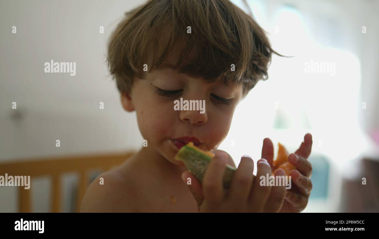 Child biting melon fruit dessert. One young boy eating healthy tasty ...