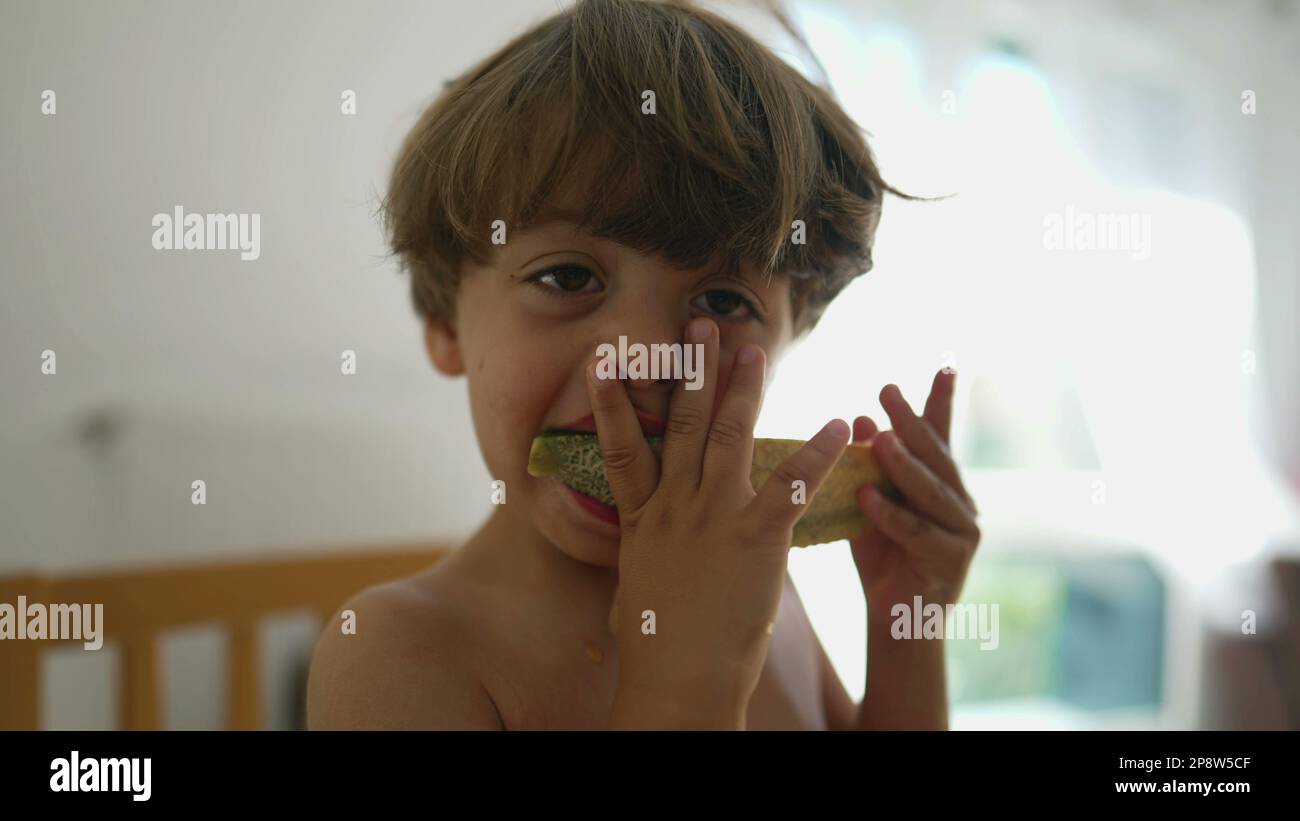 Child biting melon fruit dessert. One young boy eating healthy tasty ...