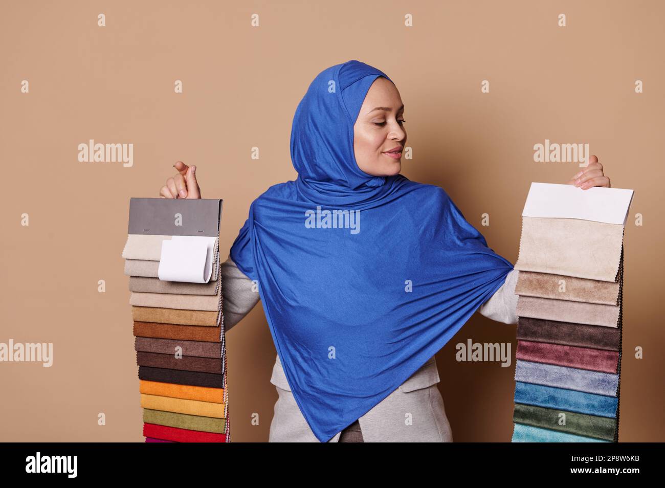 Muslim female interior designer in blue hijab presents at camera fabric ...